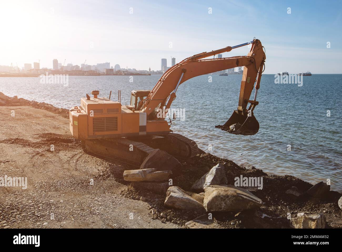 Excavator working on earthmoving at construction of new embankment ...