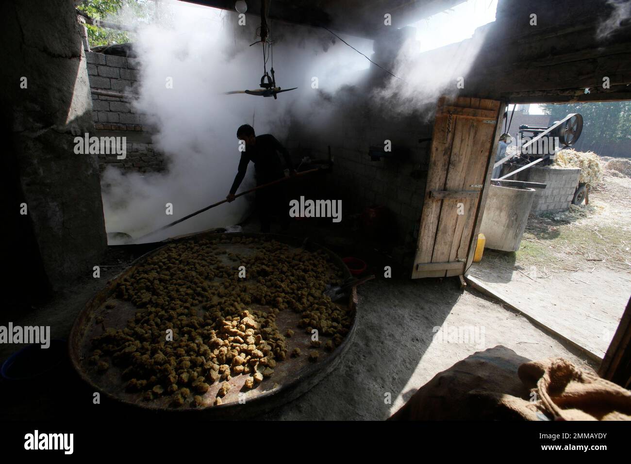 A Pakistani farmer boils sugarcane juice to make a traditional sweet ...