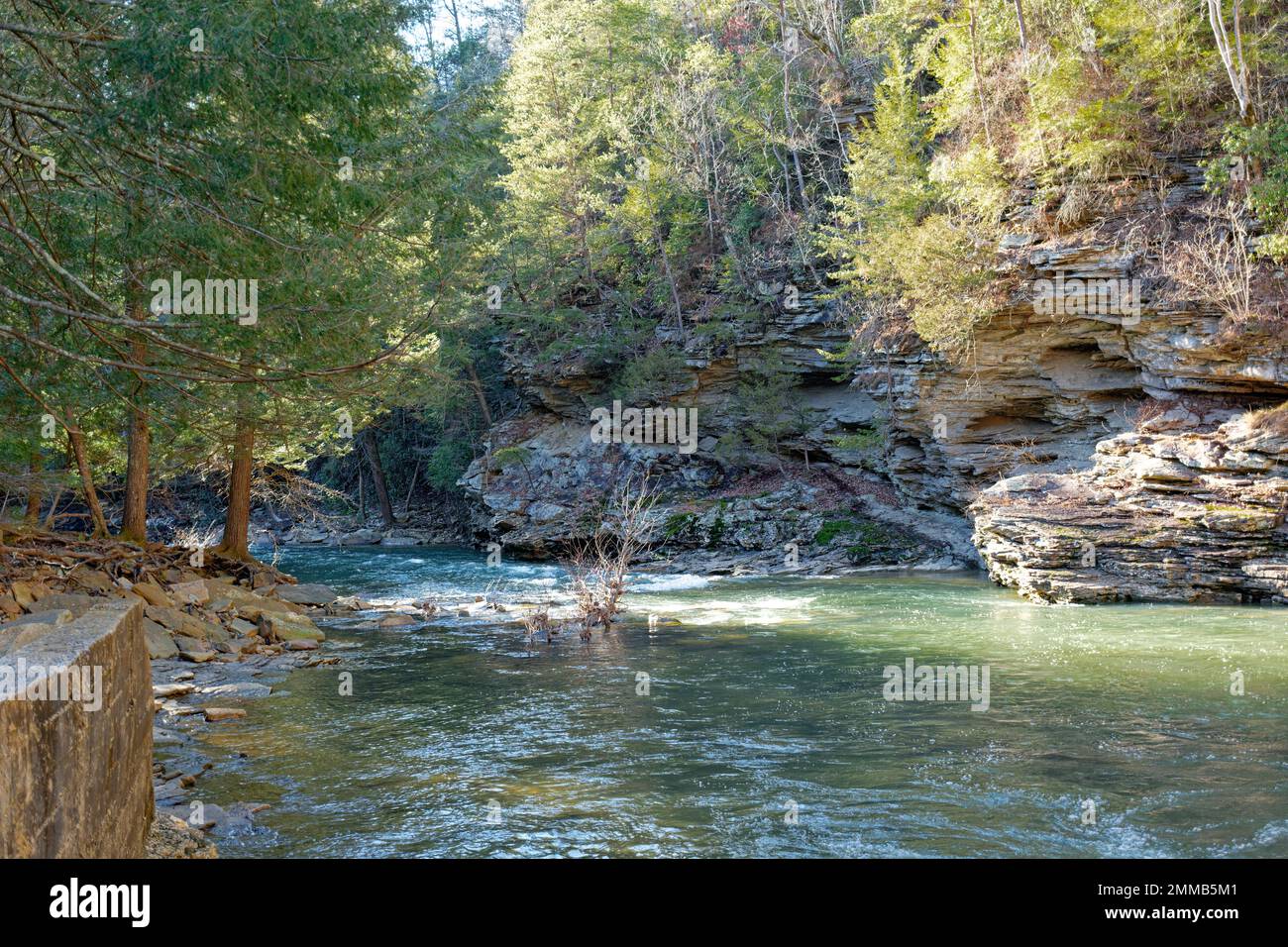 A shallow river flowing through a gorge downstream into the sunlight ...