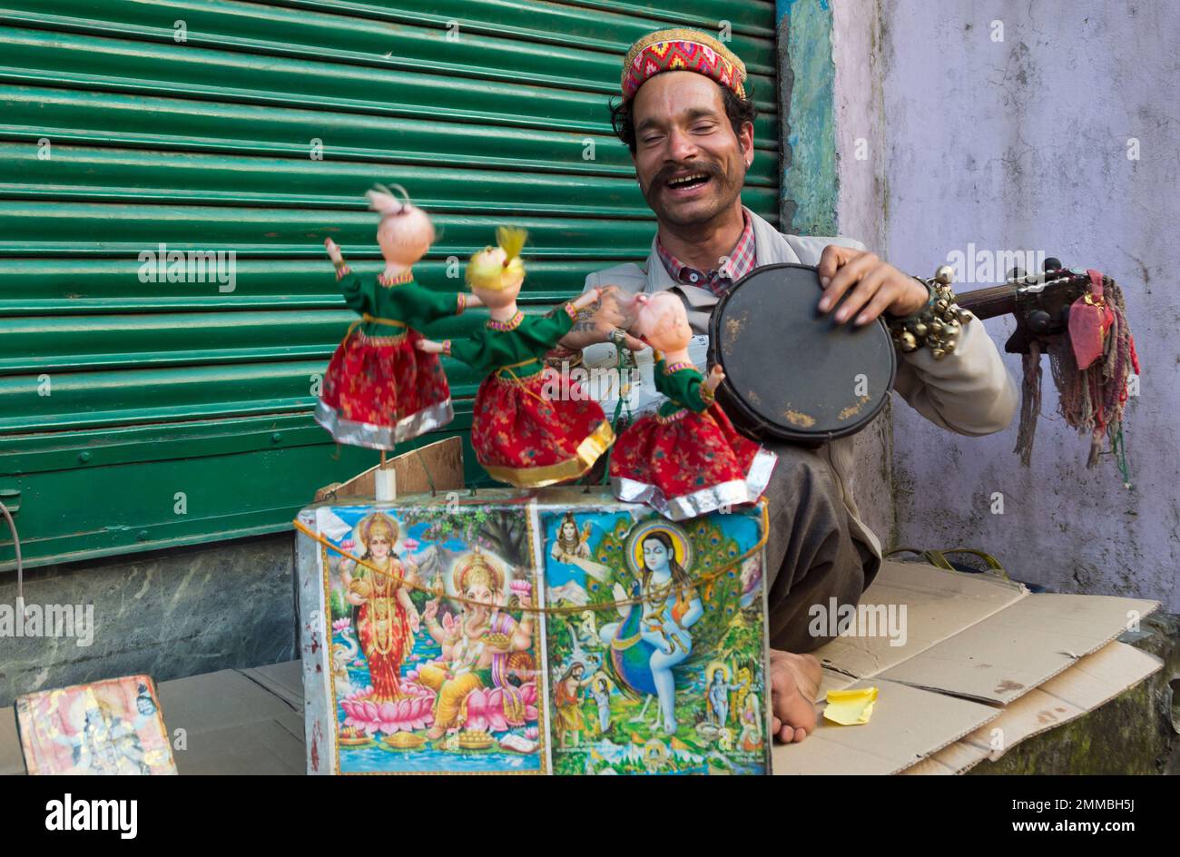 A street musician uses a lute, a drum and plastic puppets to perform a ...