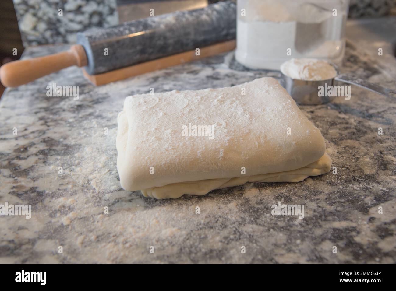 homemade Rough puff pastry with flour and a rolling pin on a marble ...