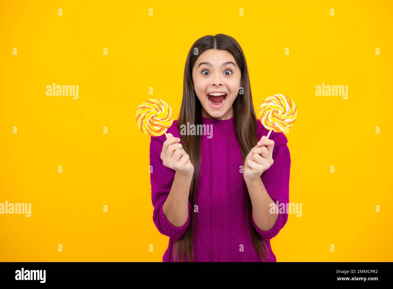 Excited face. Child eat lollipop popsicle over yellow isolated ...