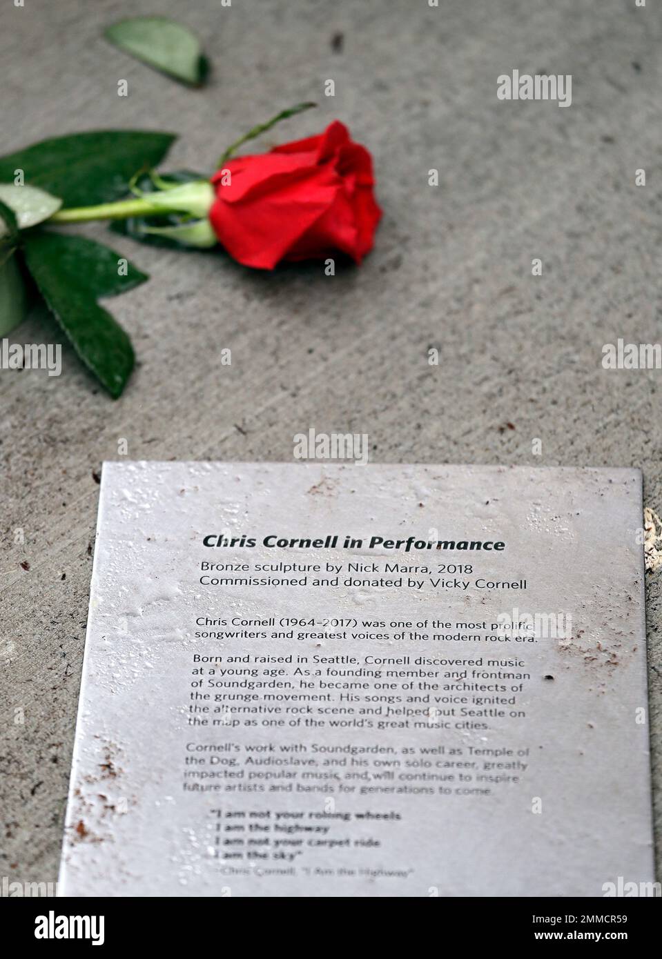 A plaque sits at the base of a life-size, bronze statue of late ...