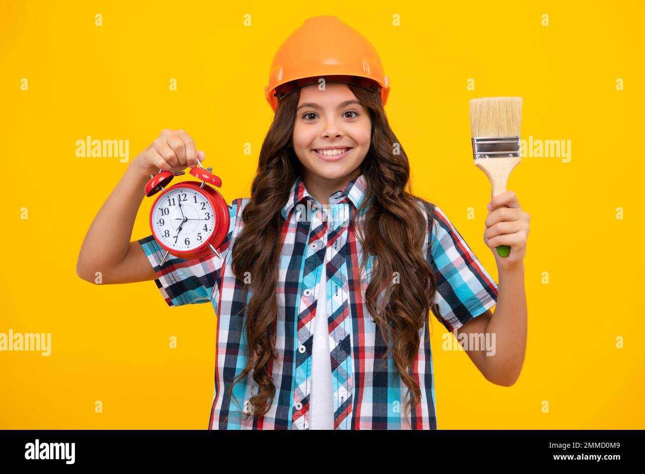 Little builder expert in helmet on construction site. Teen girl painter ...