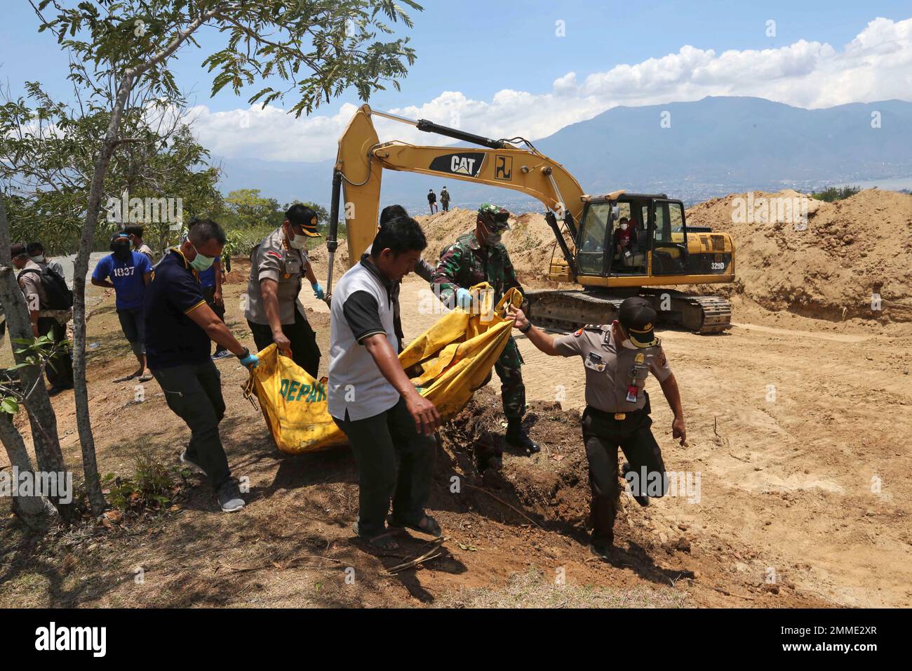 Indonesian police carry the body of a tsunami victim during a mass burial in Palu, Central ...