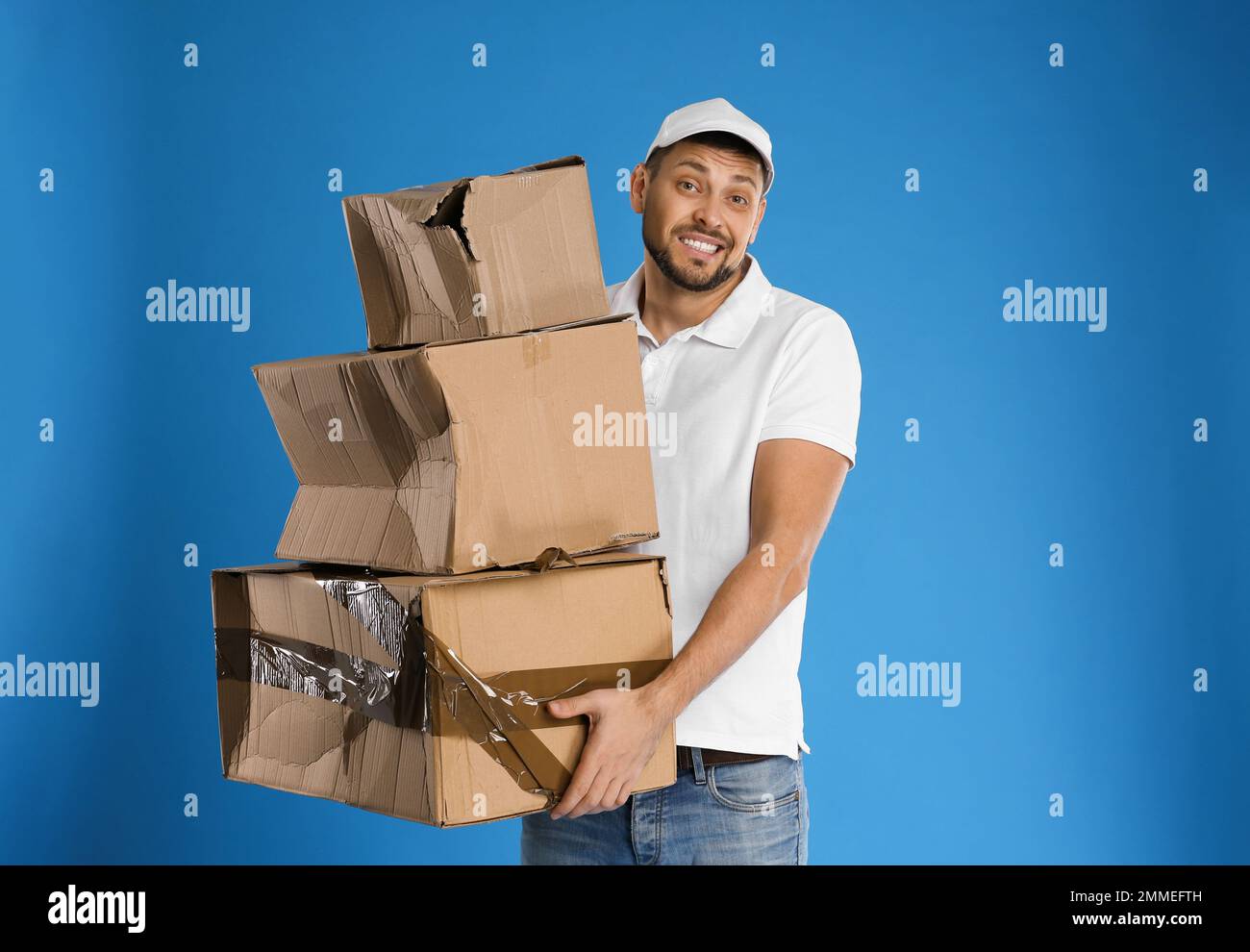 Emotional courier with damaged cardboard boxes on blue background. Poor ...