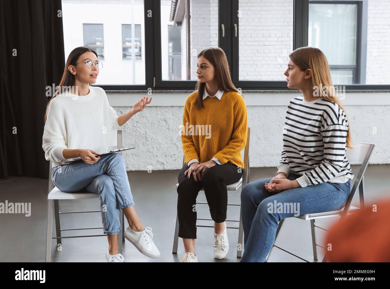 Psychotherapist working with patients in group therapy session indoors ...