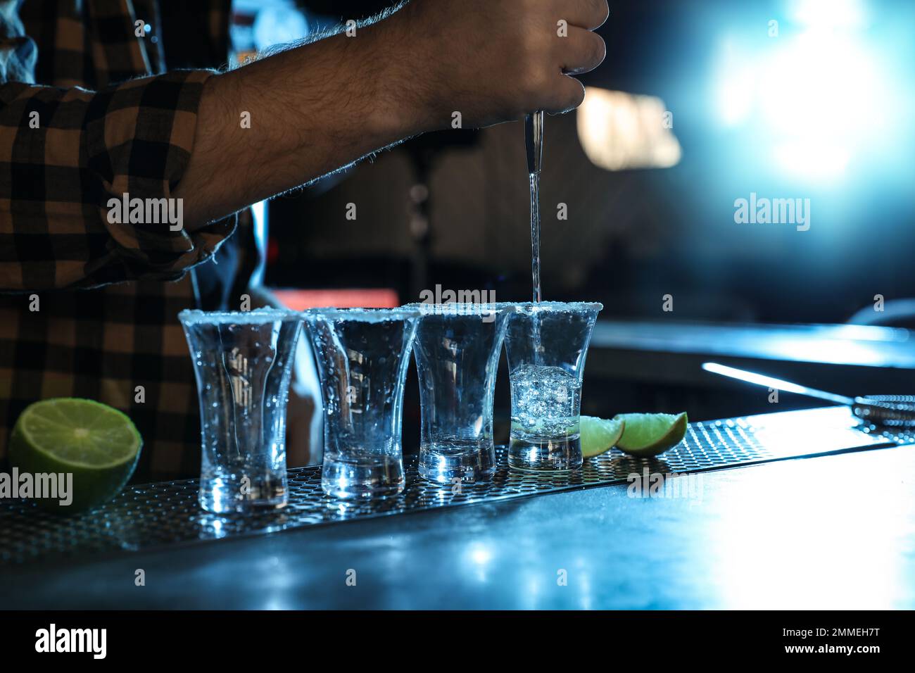 Bartender pouring Mexican Tequila into shot glasses at bar counter ...
