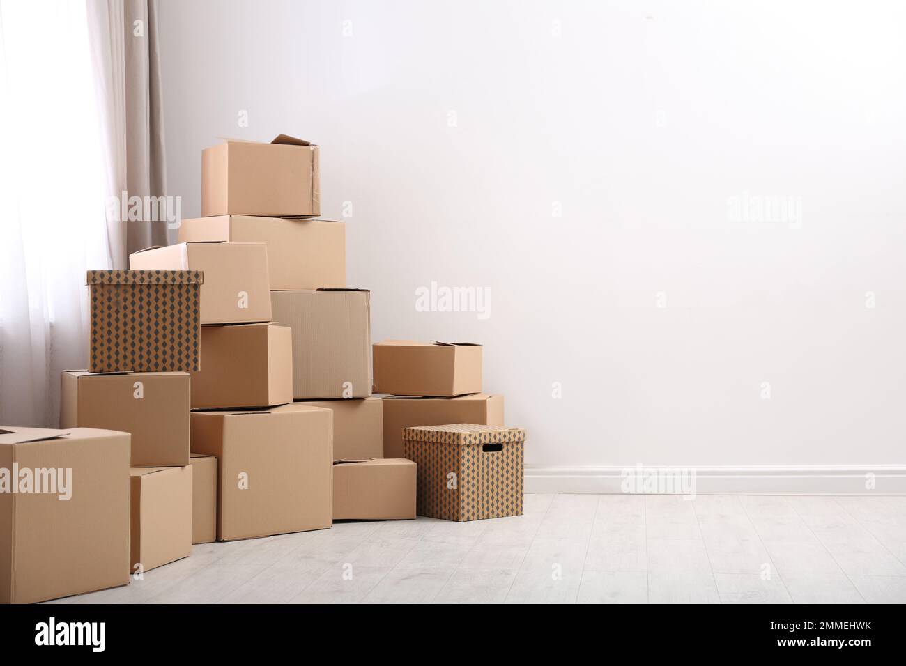 Pile of moving boxes in empty room, space for text Stock Photo - Alamy