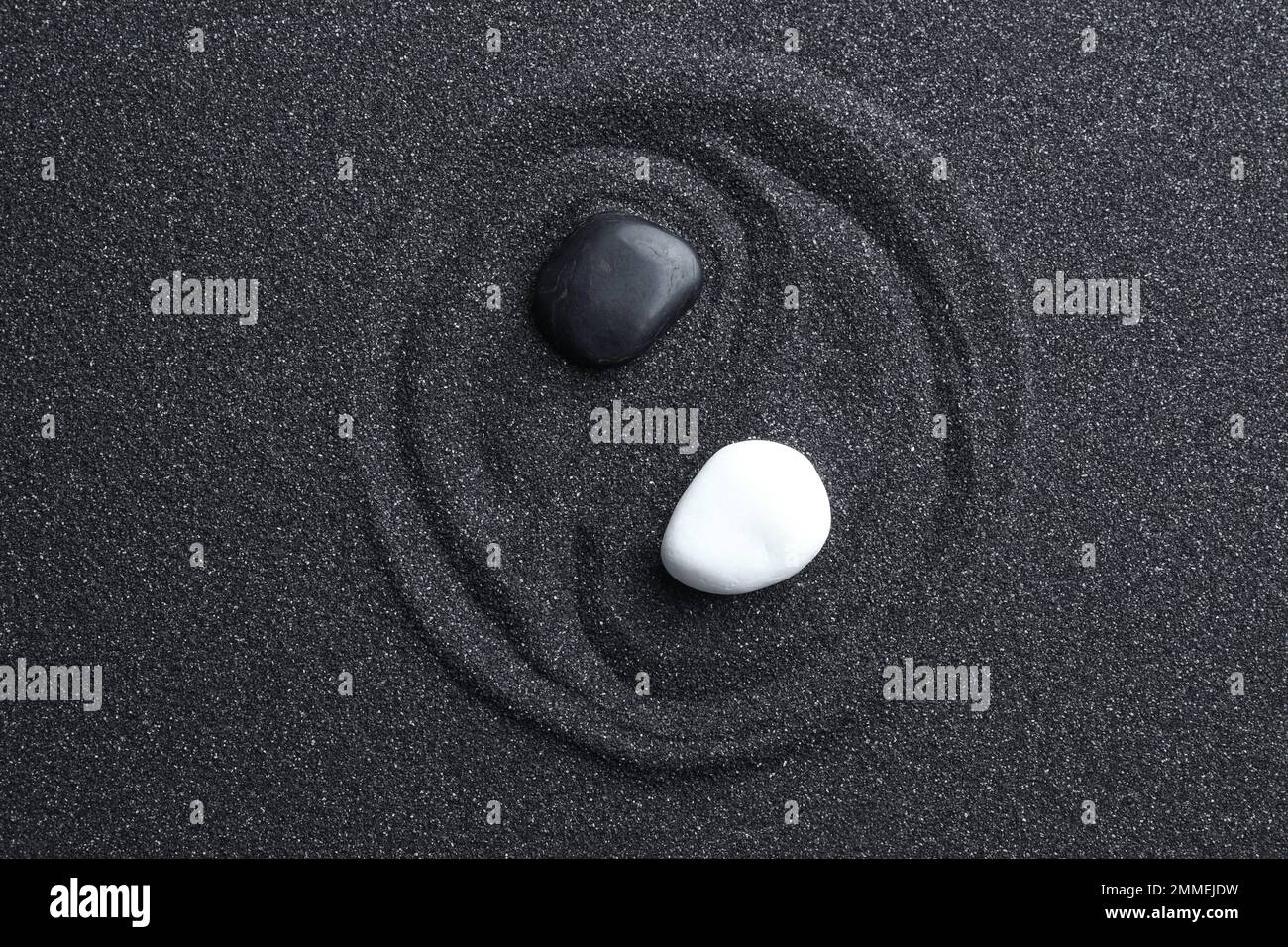 Yin Yang symbol made with stones on black sand, top view. Zen concept ...