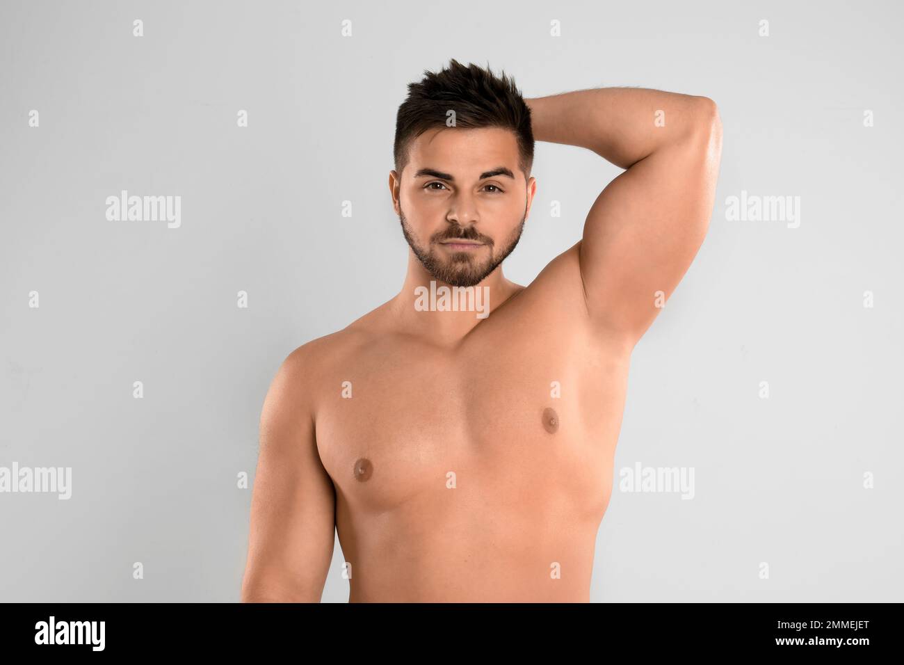Young man showing hairless armpit after epilation procedure on light ...