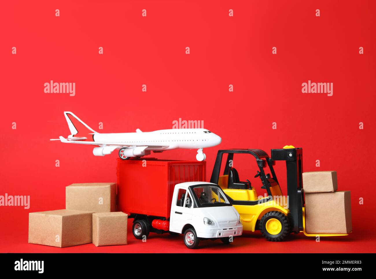 Different toy vehicles with boxes on red background. Logistics and ...