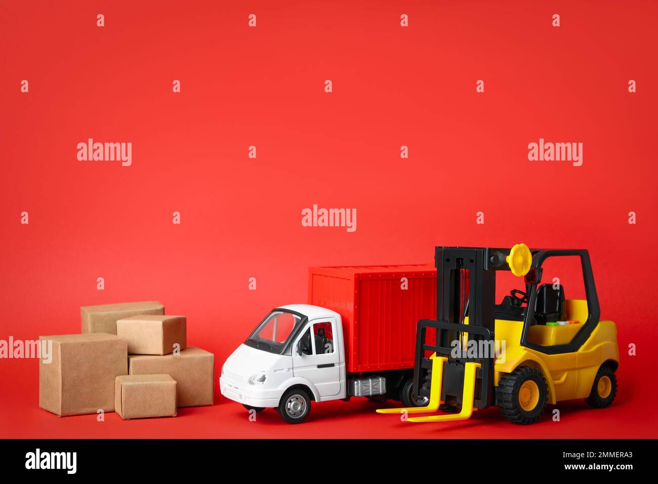 Different toy vehicles with boxes on red background. Logistics and ...