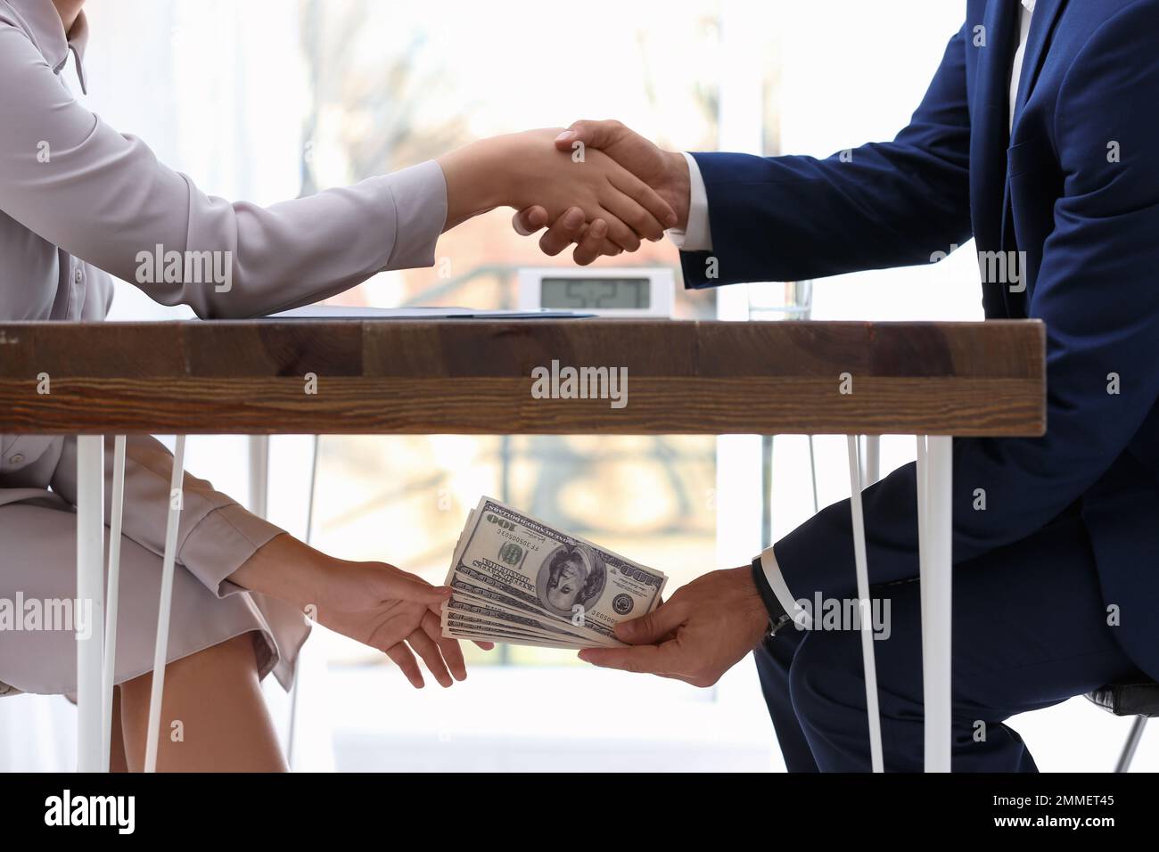 Man shaking woman's hand and giving bribe money under table, closeup ...