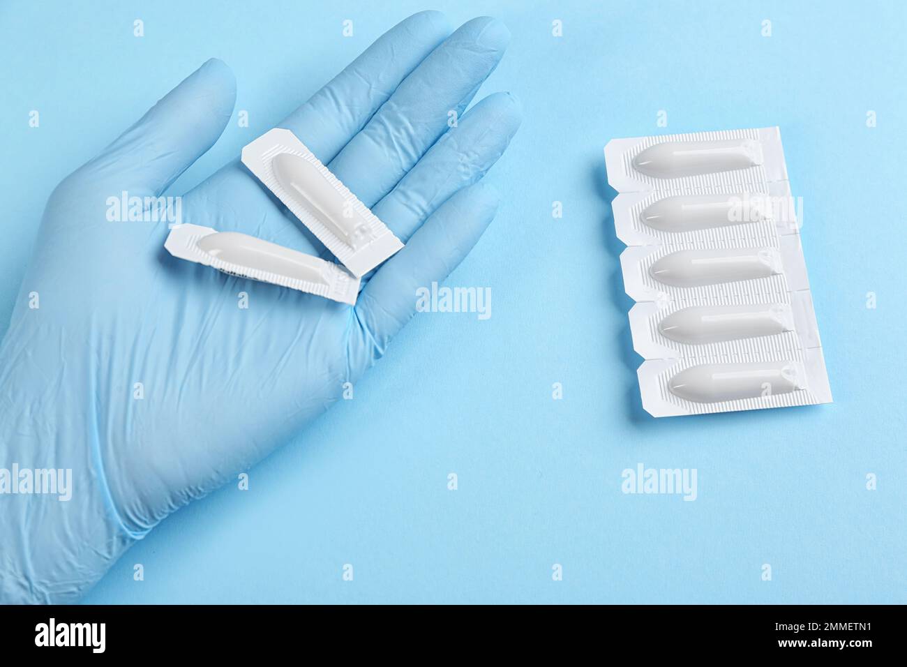 Woman holding suppositories on light blue background, top view ...