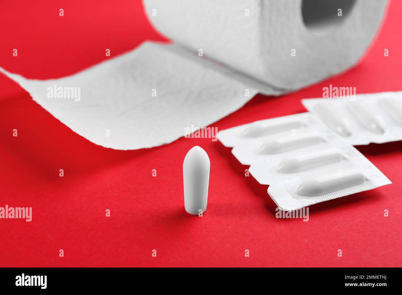 Suppositories and toilet paper on red background. Hemorrhoid treatment ...