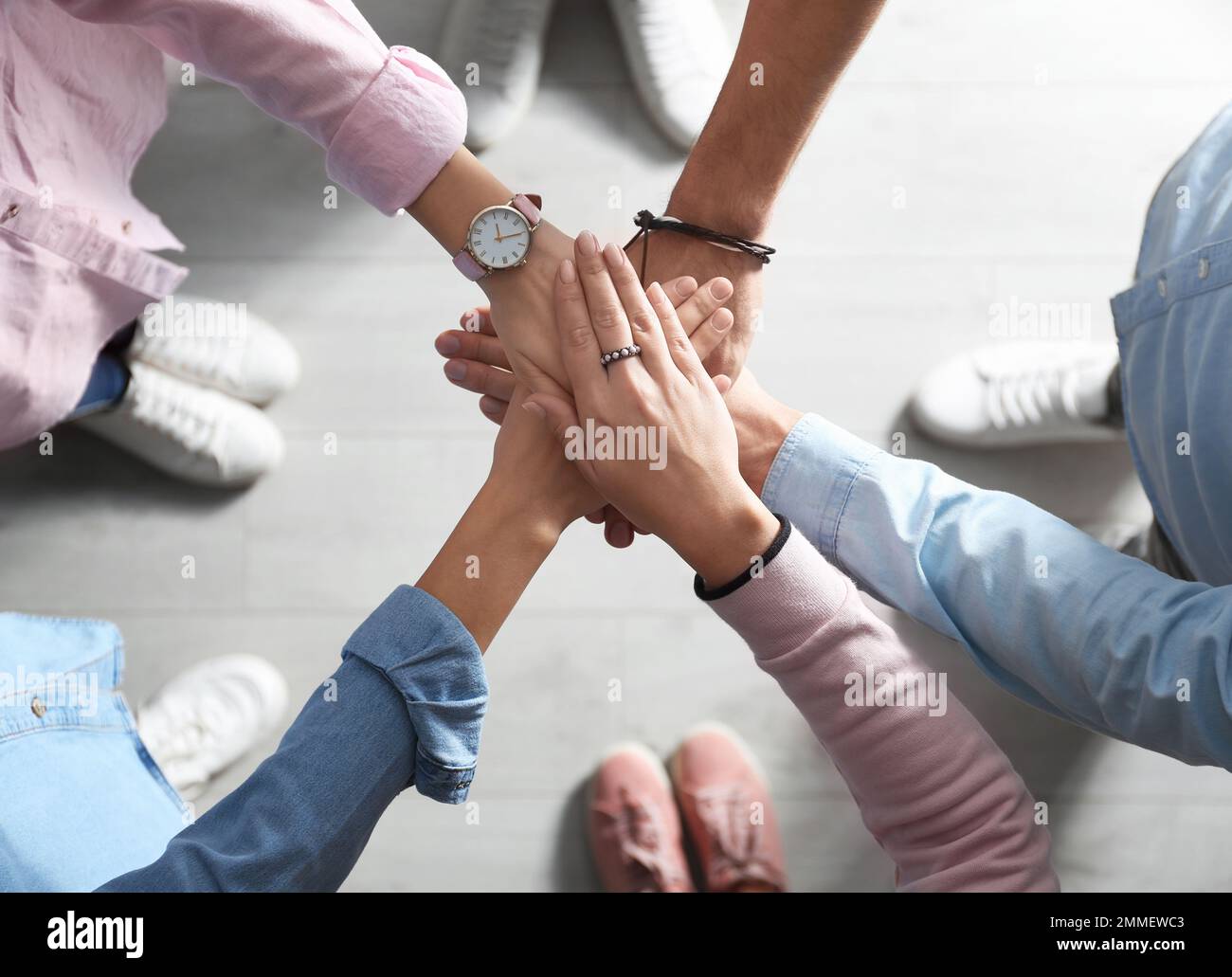 People holding hands together over light background, top view. Unity ...