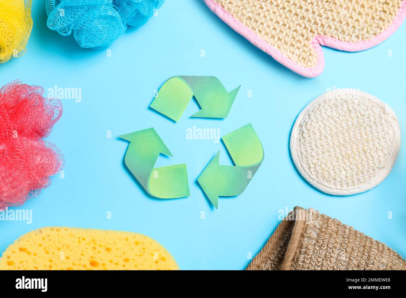 Recycling symbol, plastic and natural shower sponges on light blue ...