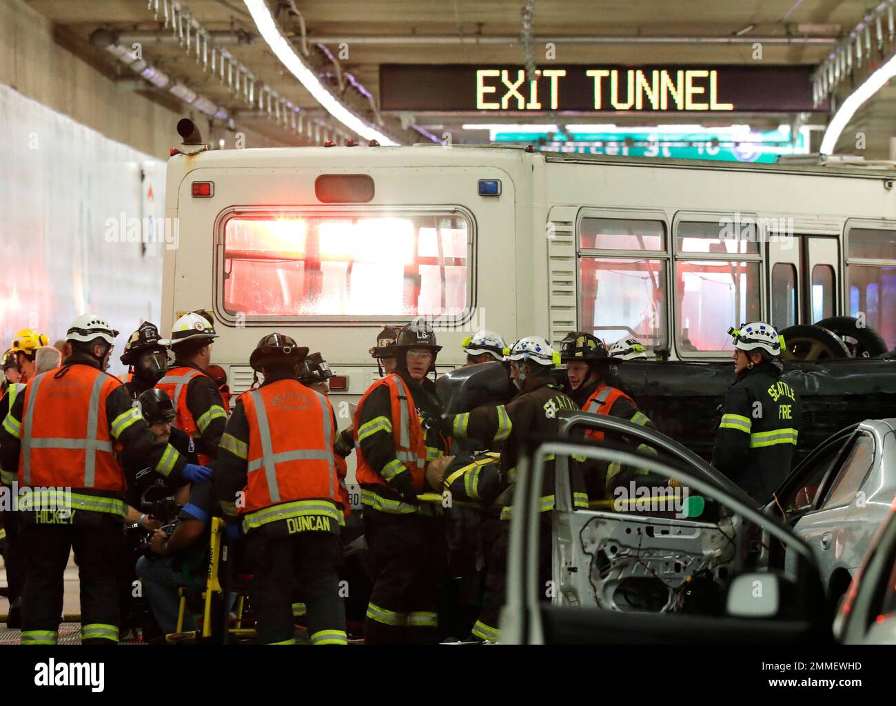 Seattle firefighters and other workers carry a stretcher from a wrecked ...