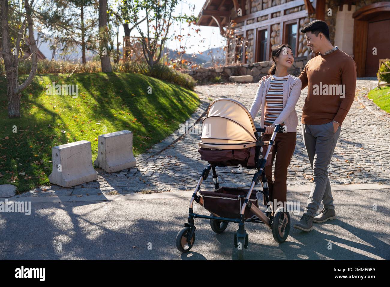A young couple walk pushing a stroller Stock Photo - Alamy
