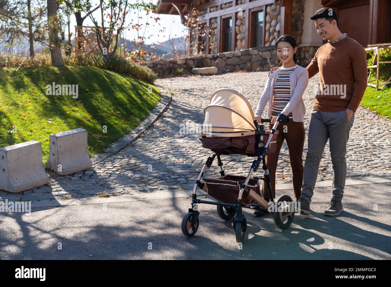 A young couple walk pushing a stroller Stock Photo - Alamy