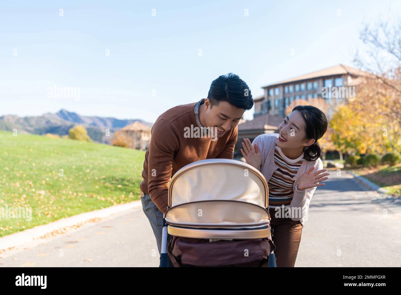 A young couple walk pushing a stroller Stock Photo - Alamy
