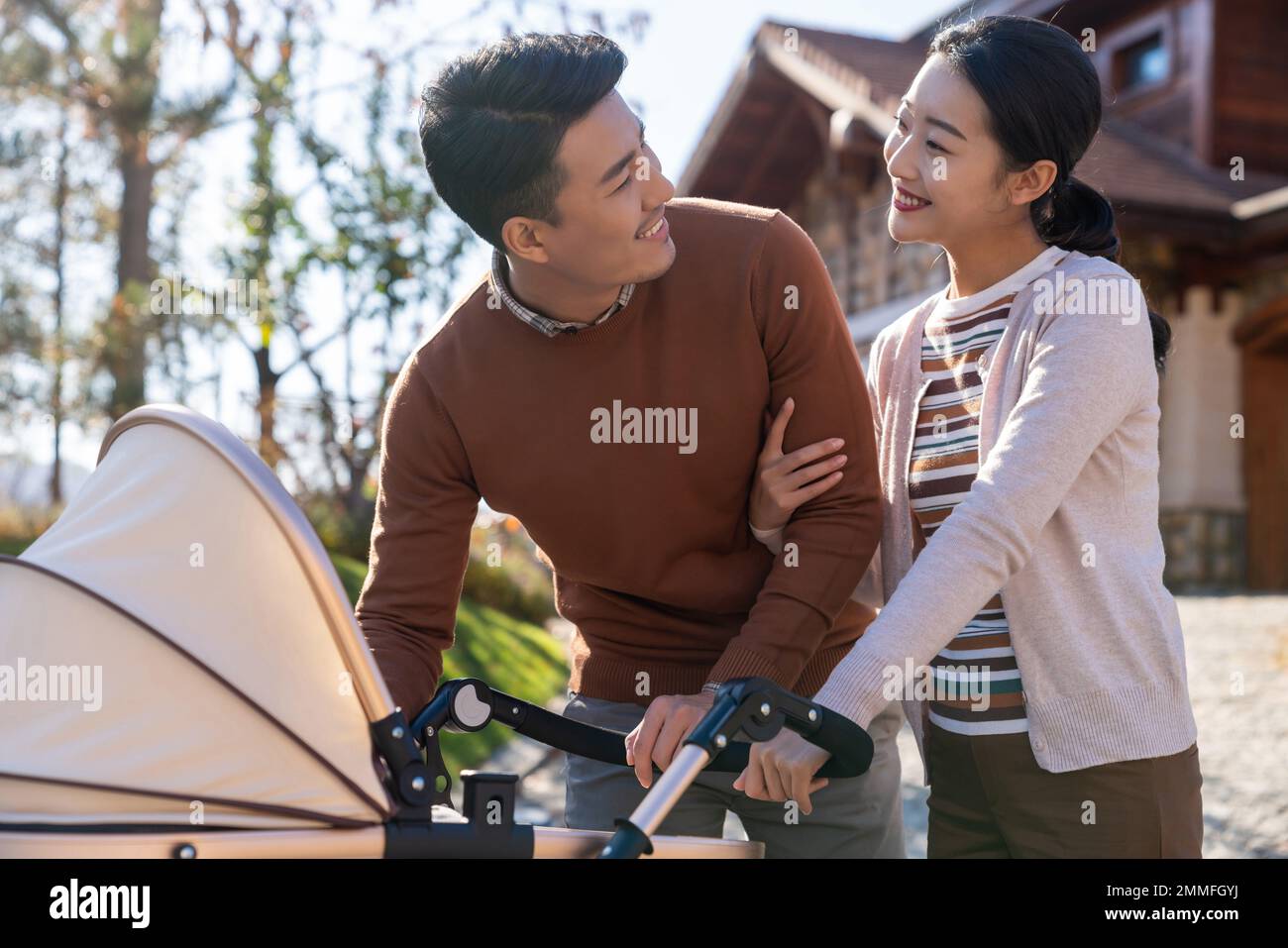 A young couple walk pushing a stroller Stock Photo - Alamy