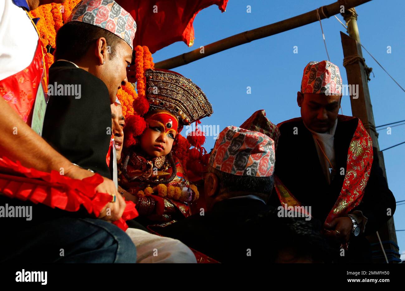 A devotee carries a living goddess locally known as Kumari, center, to ...