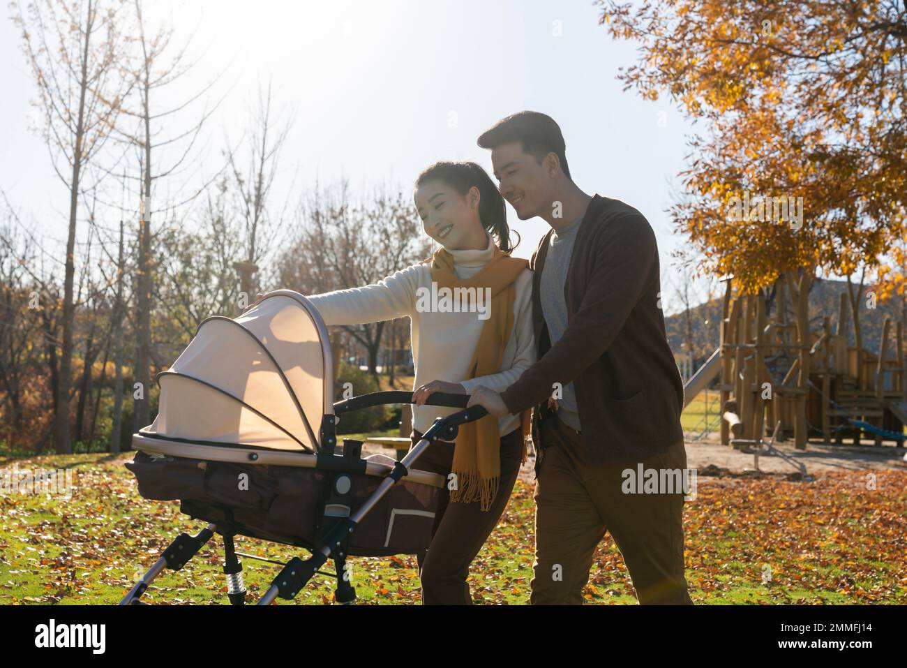 A young couple walk pushing a stroller Stock Photo - Alamy