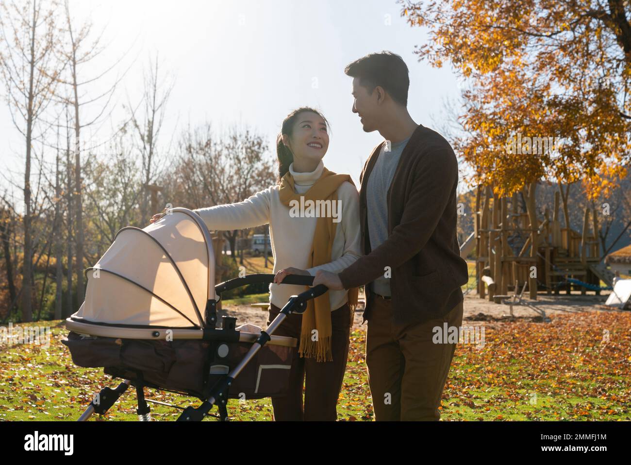 A young couple walk pushing a stroller Stock Photo - Alamy