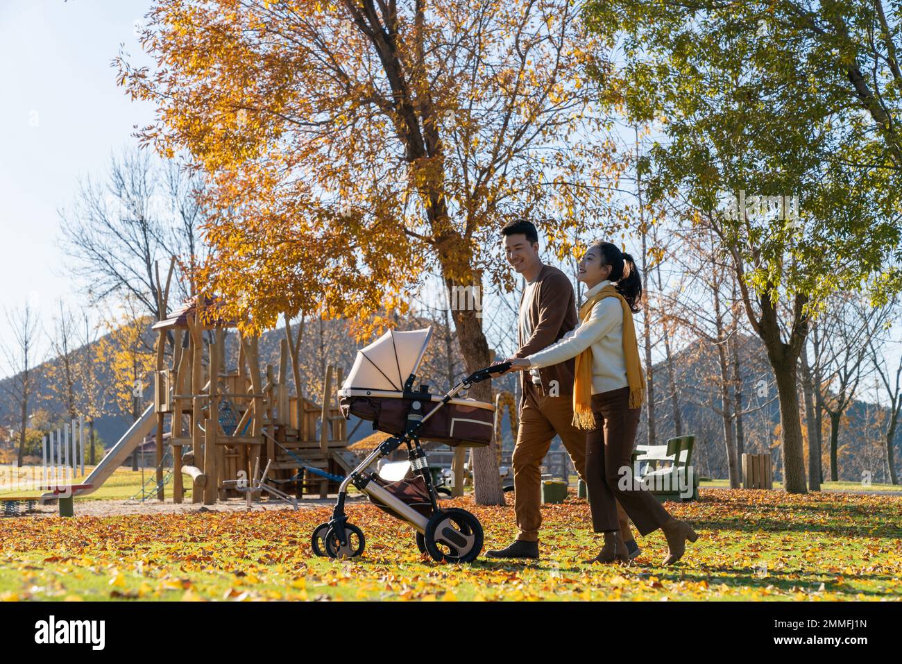 A young couple walk pushing a stroller Stock Photo - Alamy