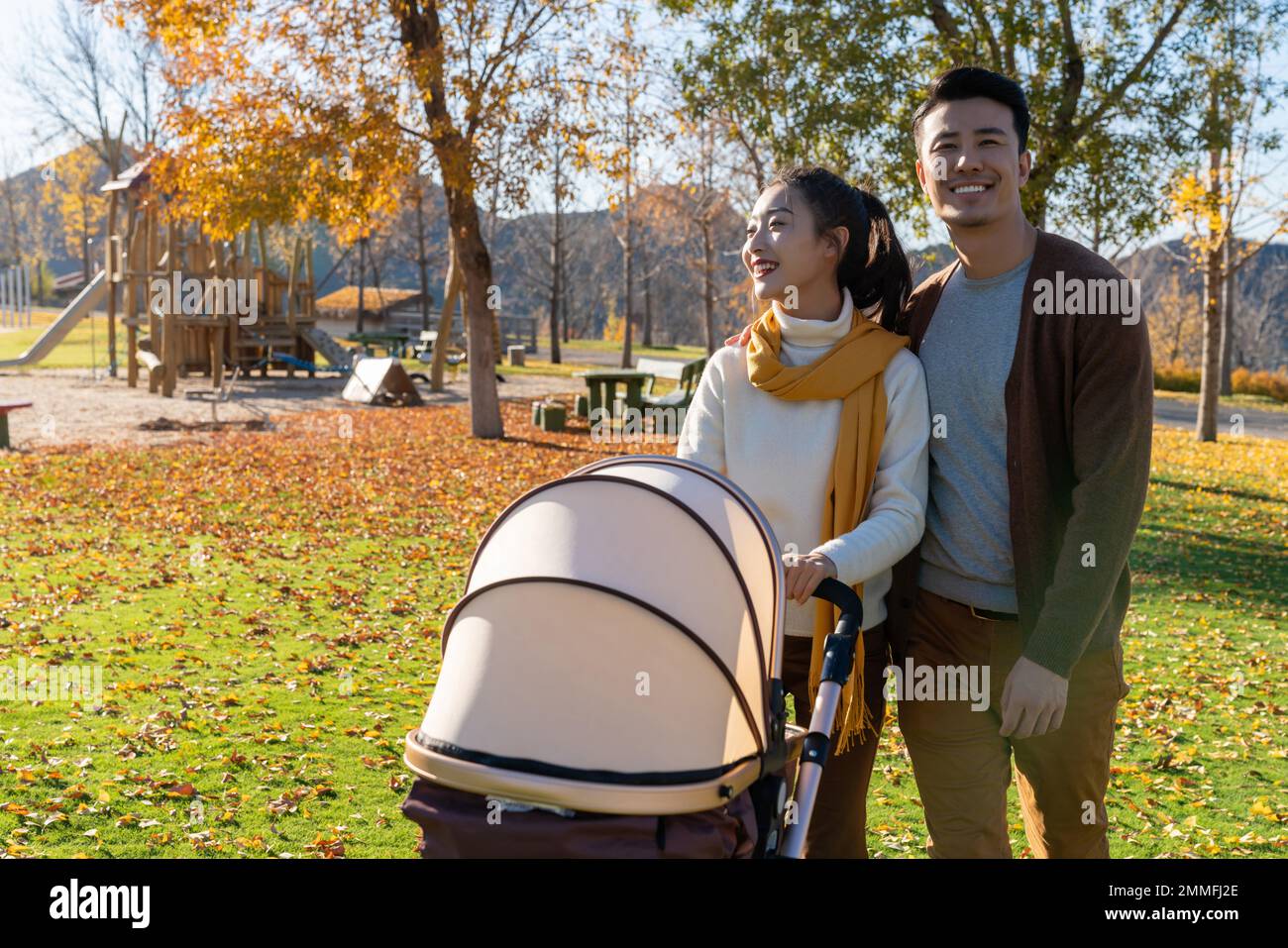 A young couple walk pushing a stroller Stock Photo - Alamy