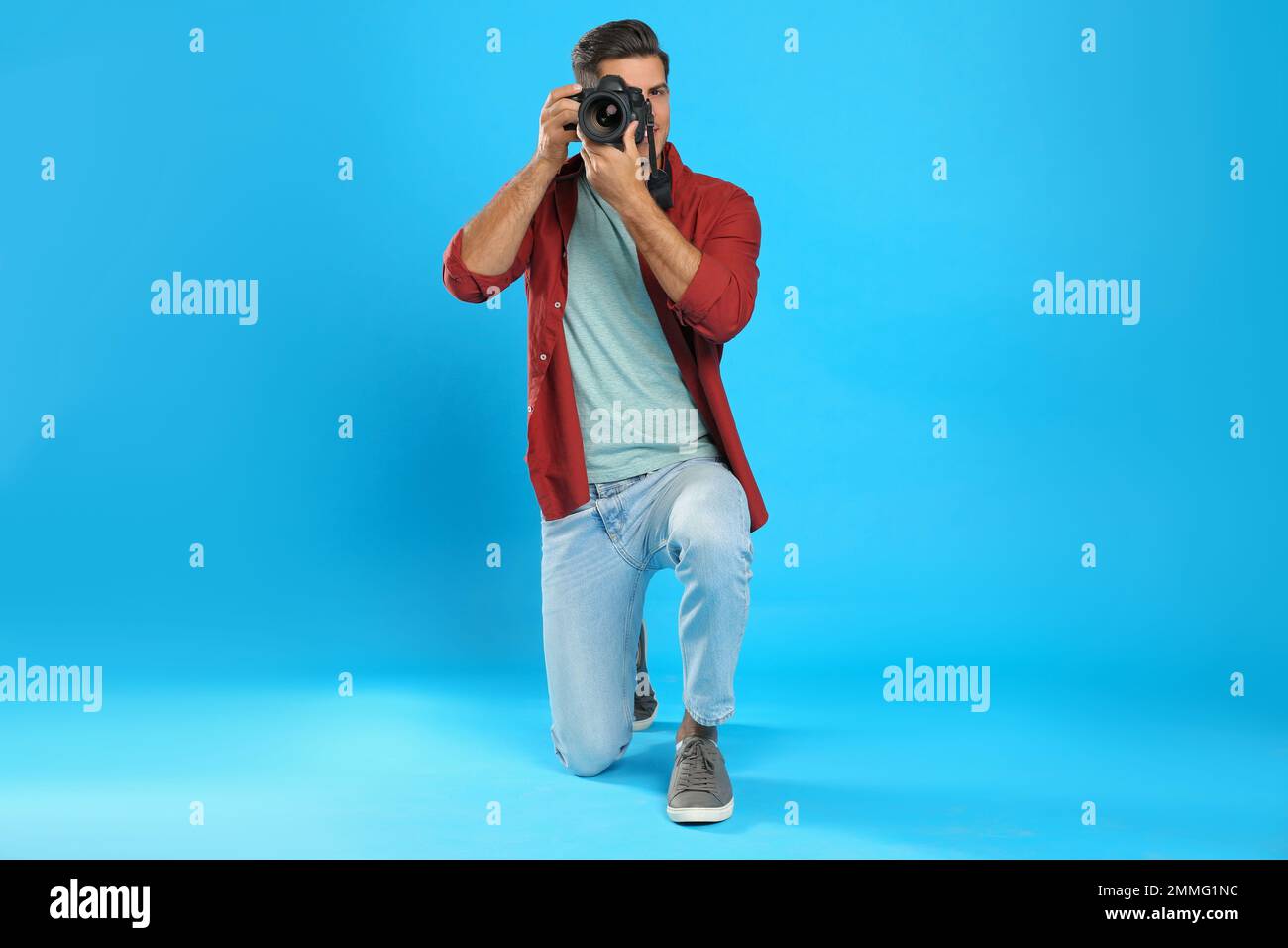 Professional photographer working on light blue background in studio ...