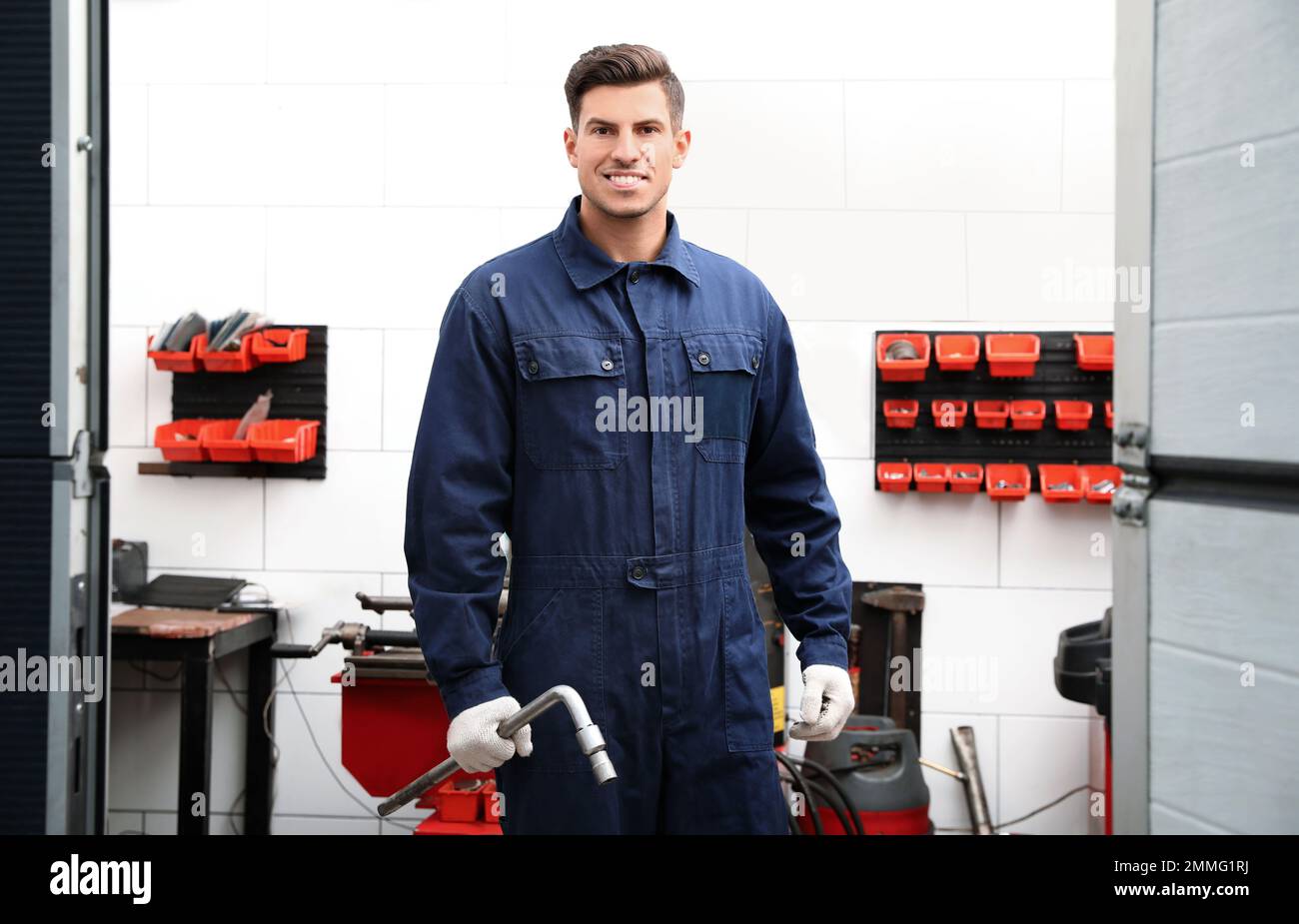 Professional worker with wheel wrench in shop of modern tire service ...