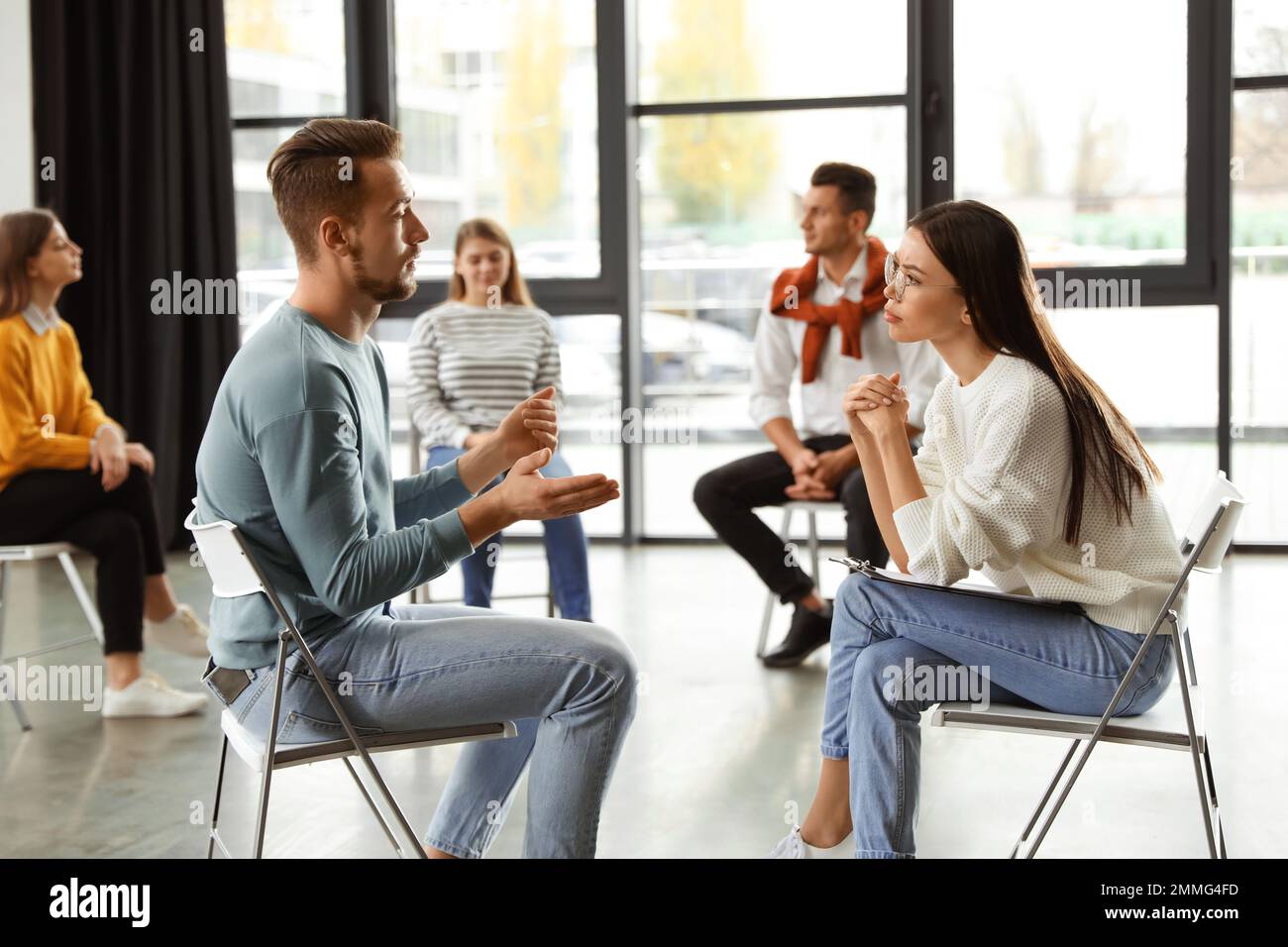 Psychotherapist working with patient in group therapy session indoors ...