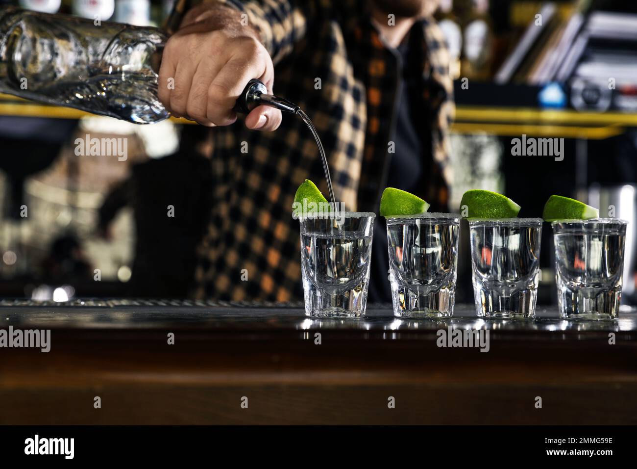 Bartender pouring Mexican Tequila into shot glasses at bar counter, closeup Stock Photo - Alamy