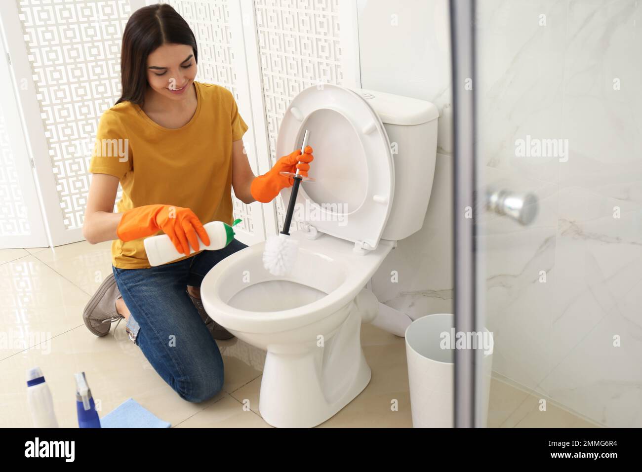 Young woman cleaning toilet bowl in bathroom Stock Photo - Alamy