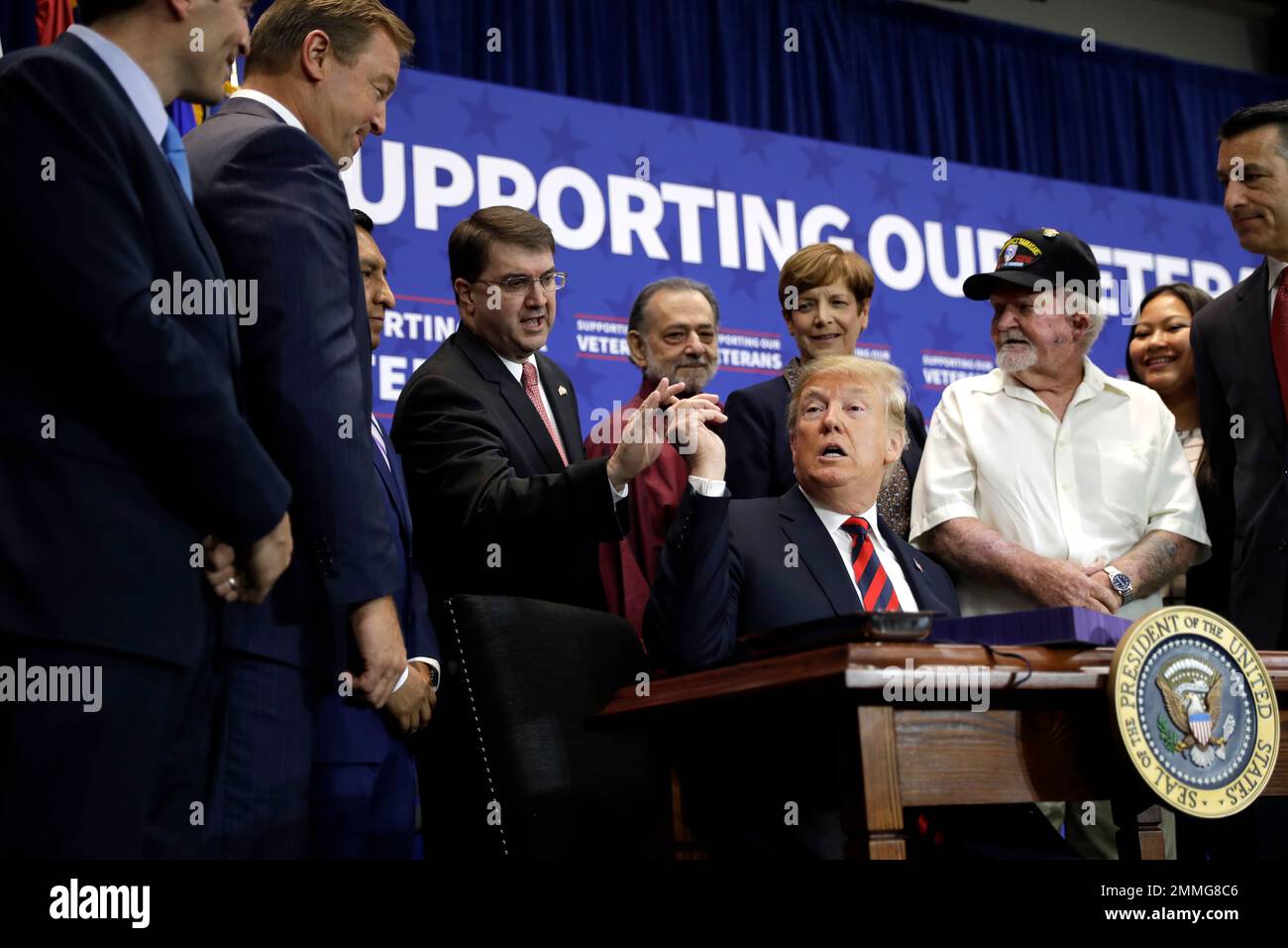 President Donald Trump hands a pen to Veterans Affairs Secretary Robert ...