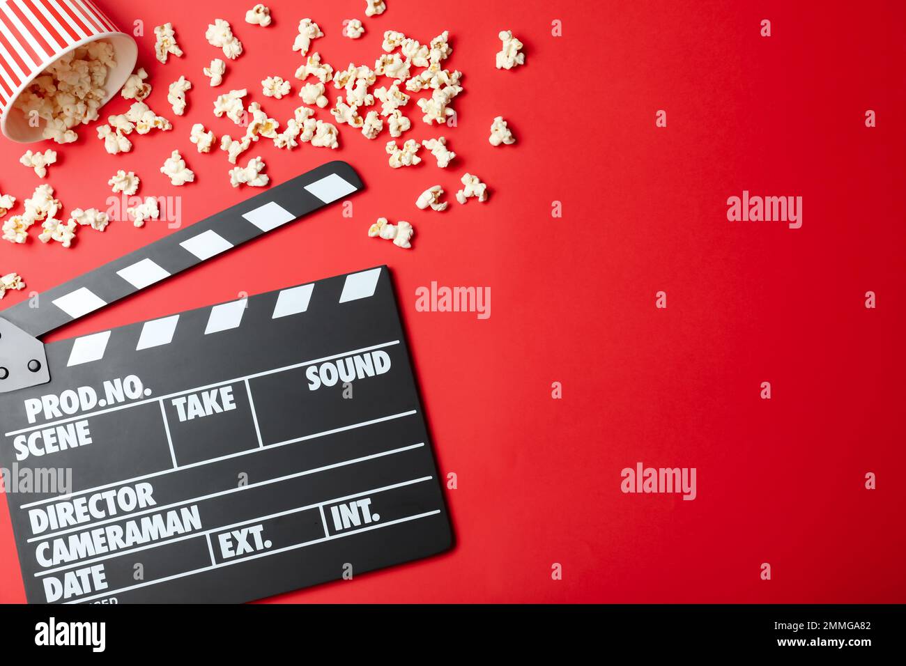 Clapper board and popcorn on red background, flat lay with space for ...