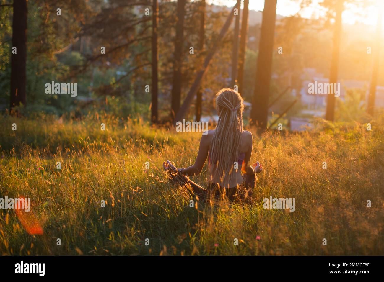 Woman in yoga pose, meditating in a sun-drenched clearing Stock Photo ...