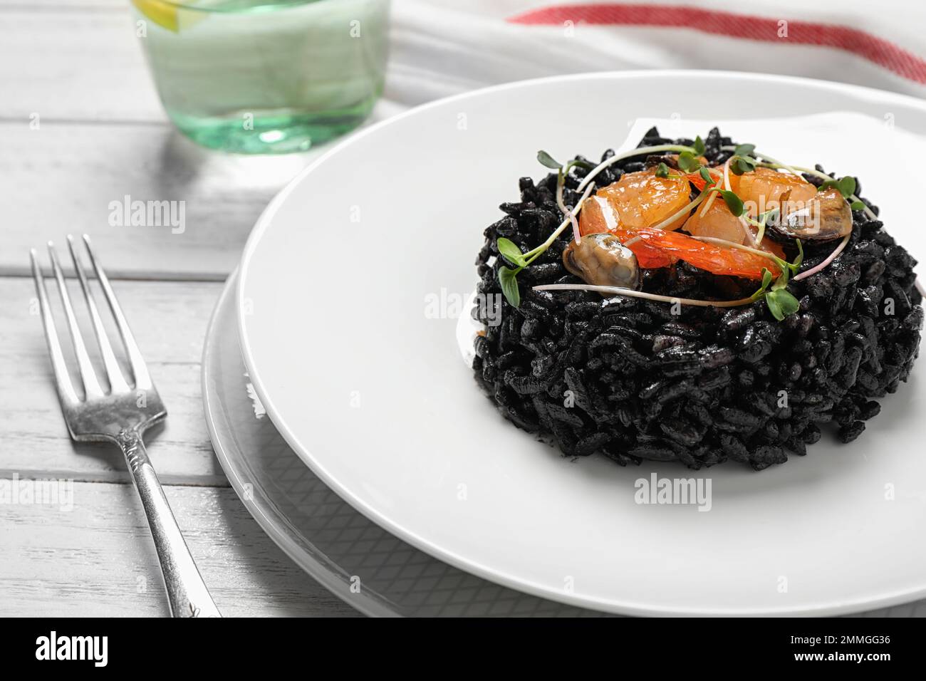 Delicious black risotto with seafood on white wooden table, closeup ...