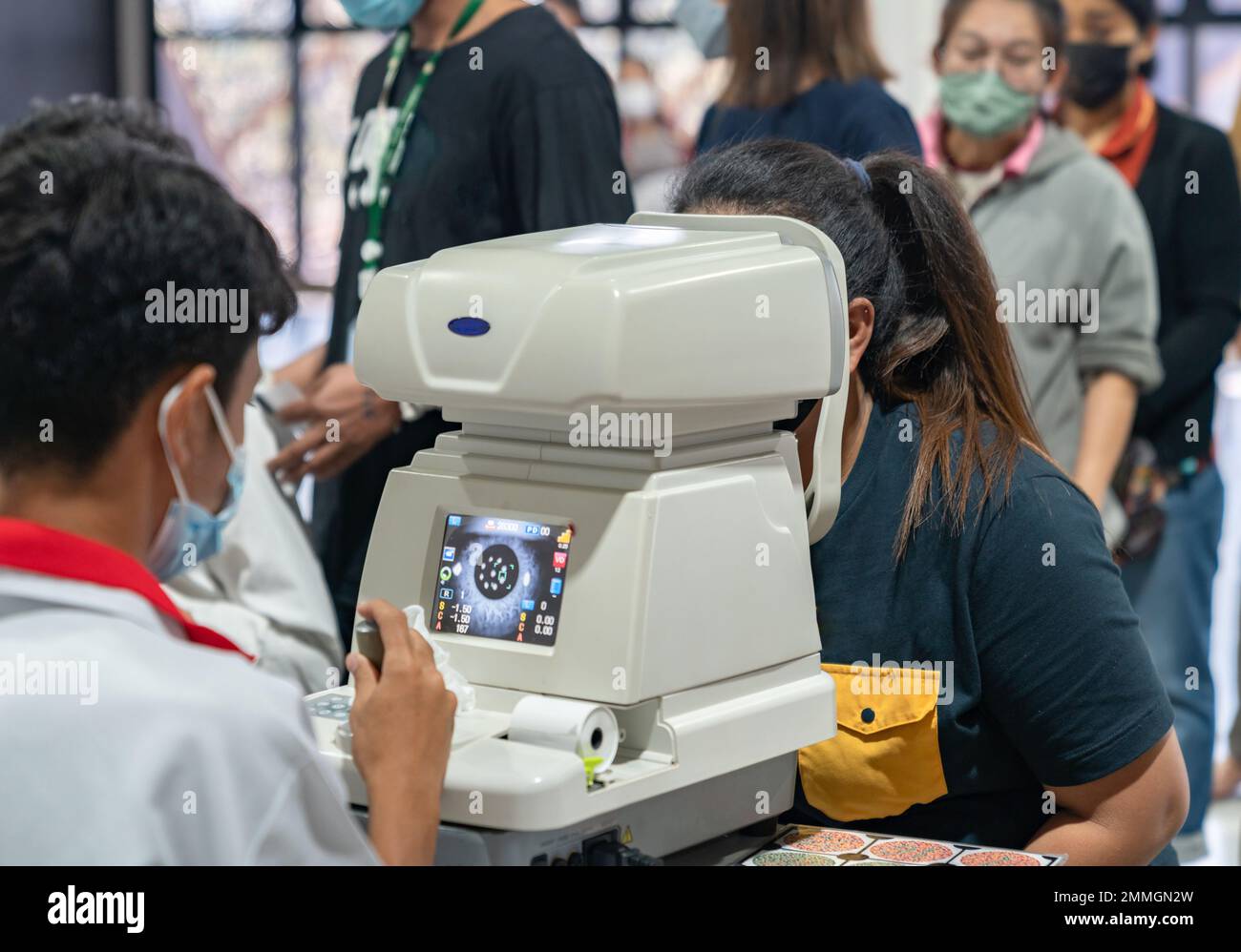 Optician examining woman's eyes with a machine in annual health check Stock Photo - Alamy
