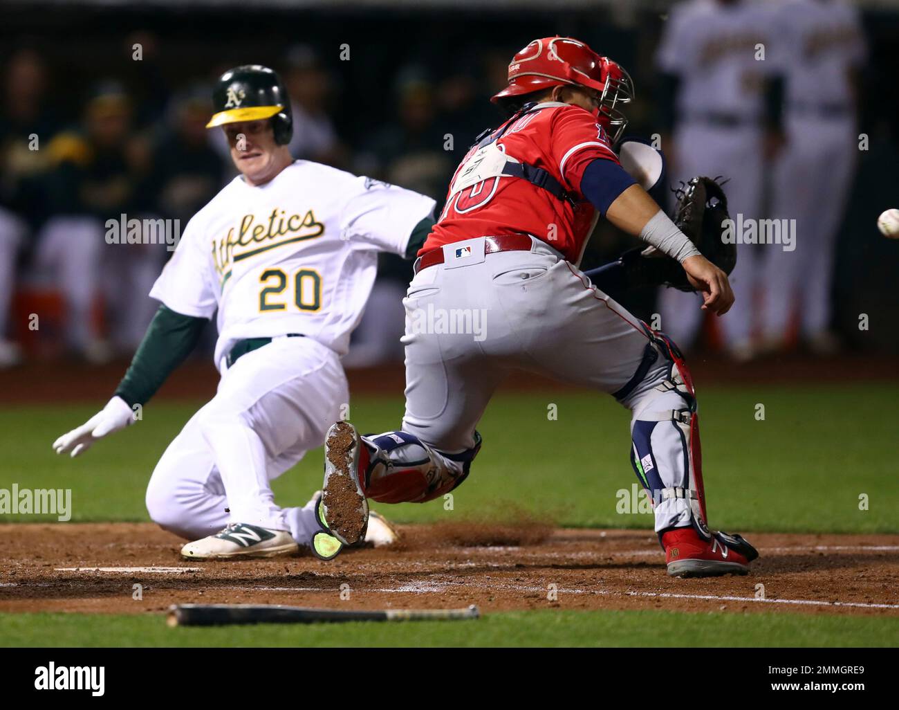 Oakland Athletics' Mark Canha (20) scores as Los Angeles Angels' Jose ...