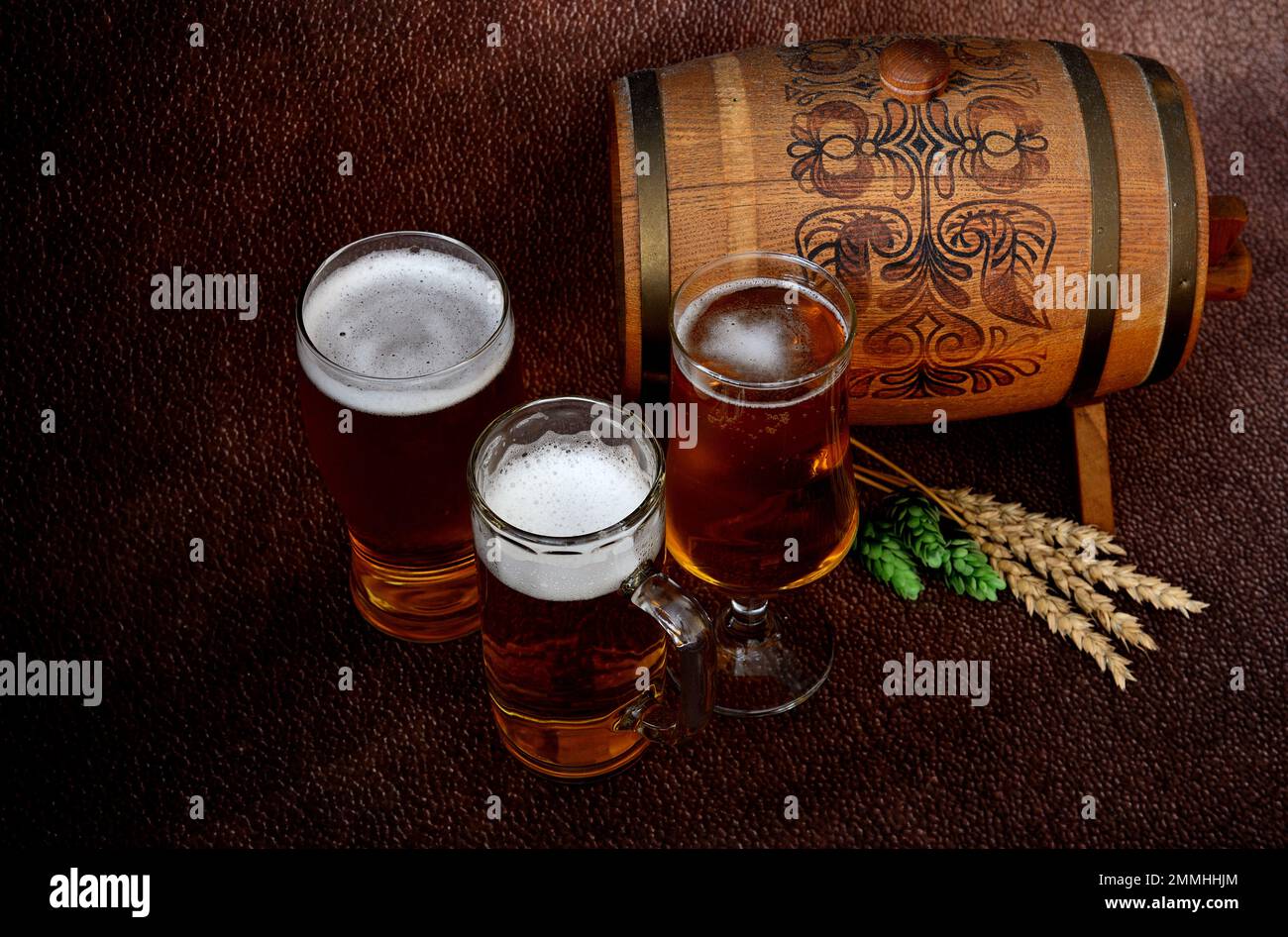 Three different glasses with light beer, a wooden keg, ears of barley ...