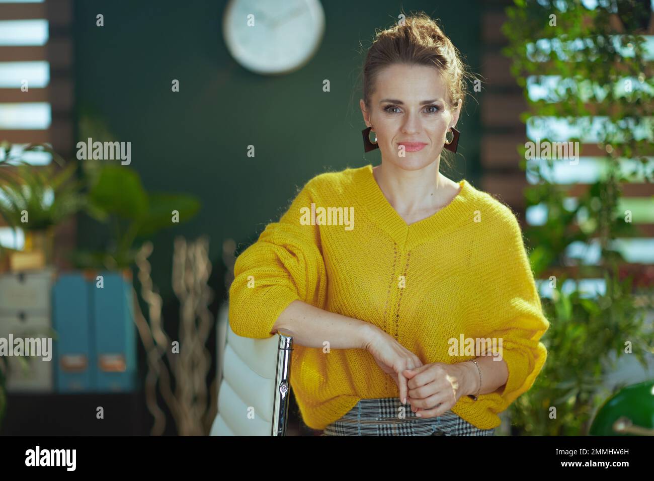 modern small business owner woman in yellow sweater standing in the ...
