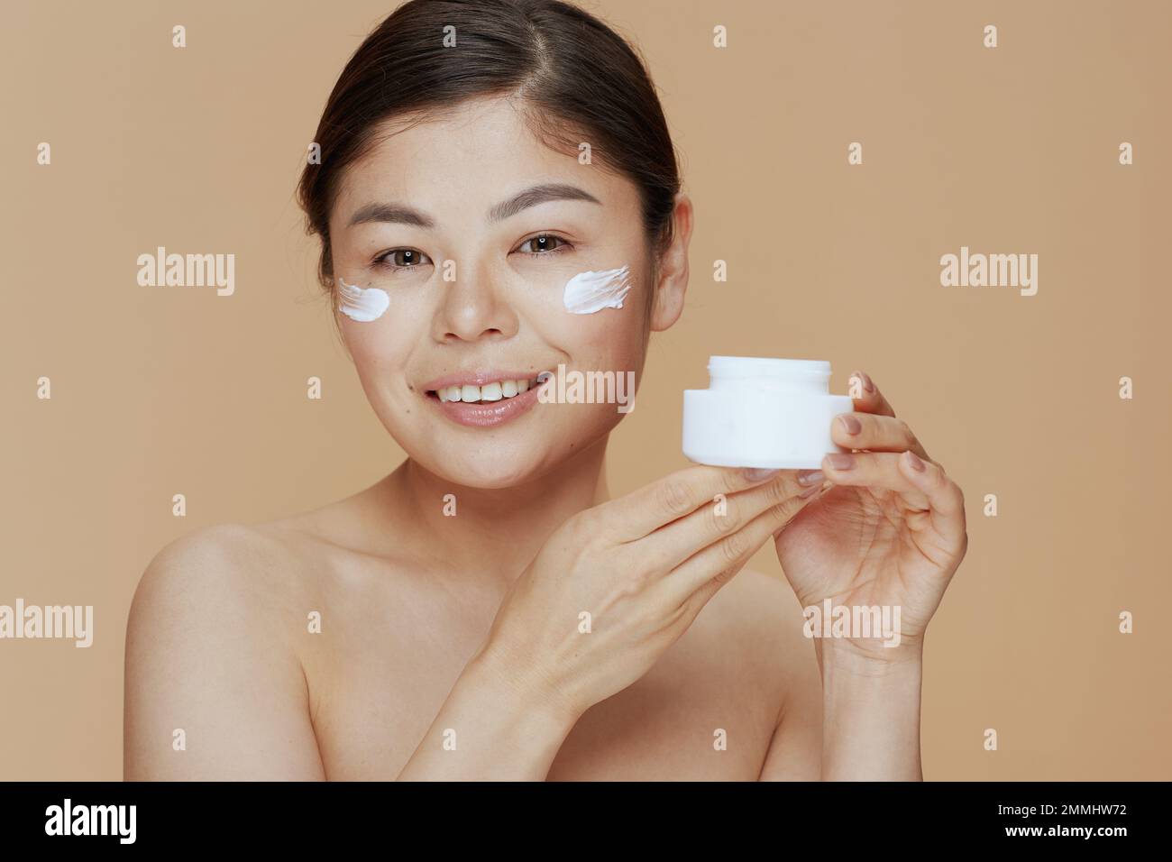 Portrait of modern asian woman with facial cream jar and facial cream ...