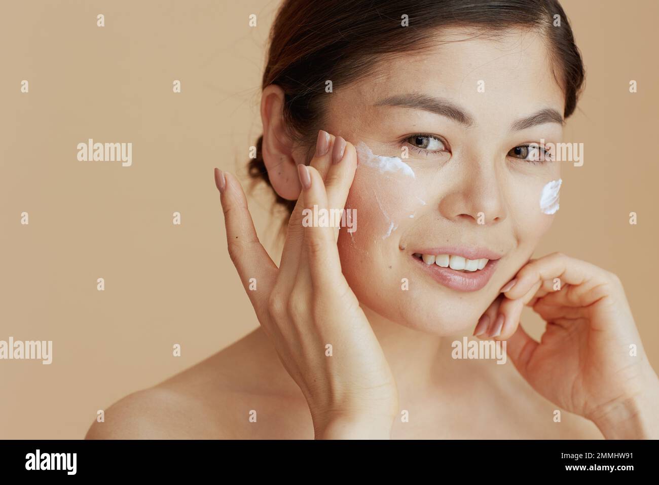 Portrait of modern asian female with facial cream on face isolated on ...
