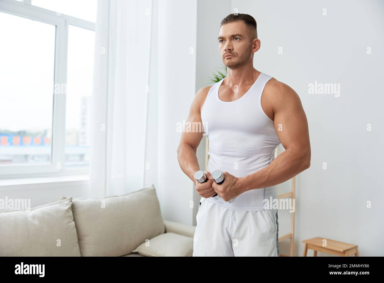 Man sportsman training at home with dumbbells, exercises for arms and ...