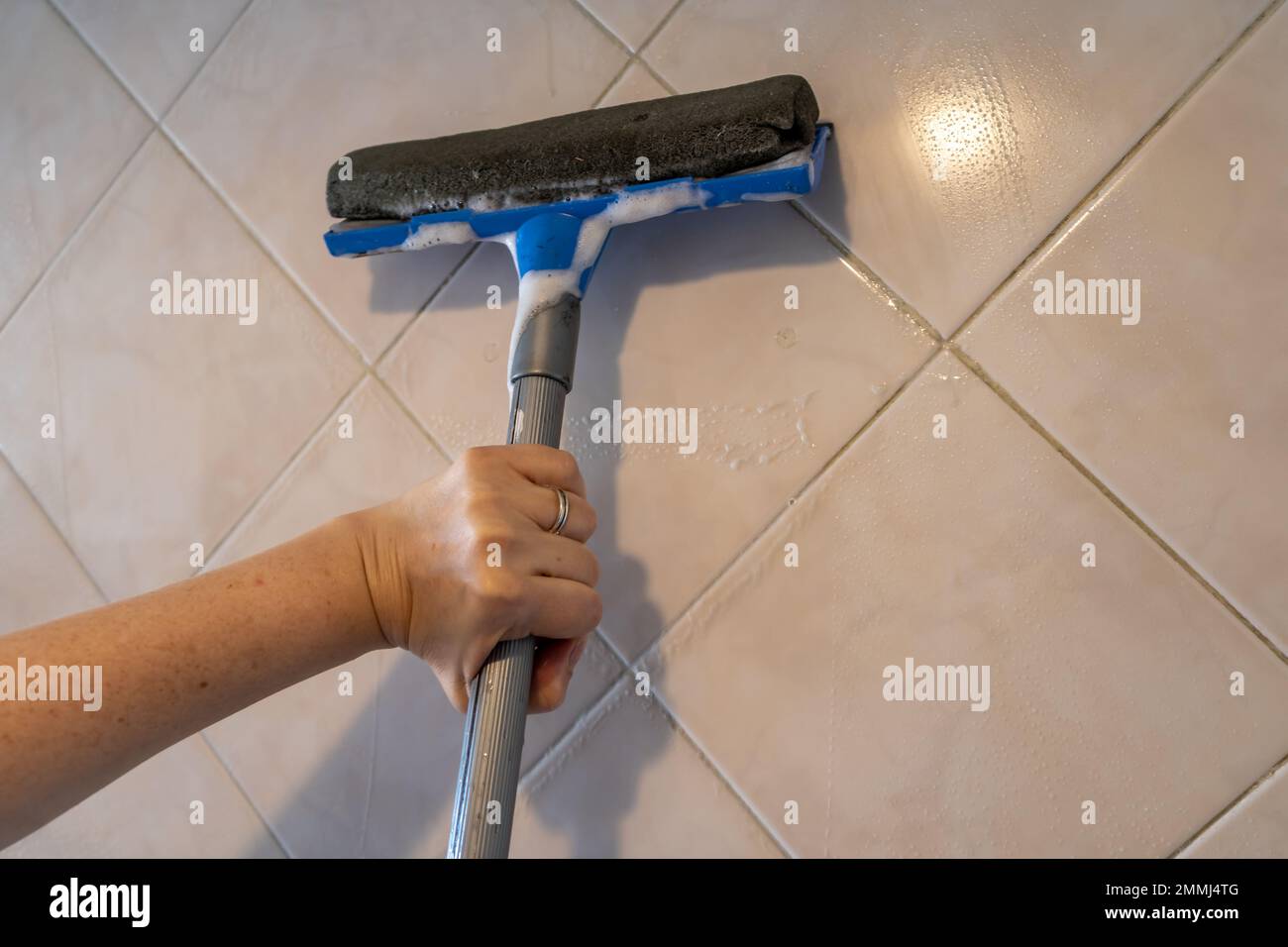 A Woman's hands holding a wall dryer cleaning tiles. Landscape ...