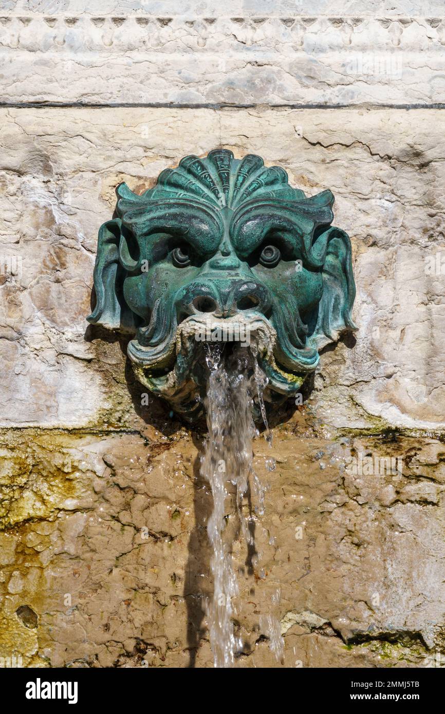 Old metal fountain decoration of a face with water shooting from the ...